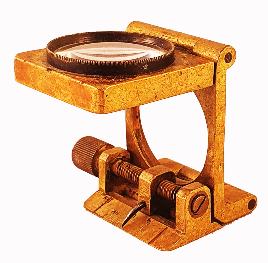 A gold metal device with a magnifying glassDescription automatically ...