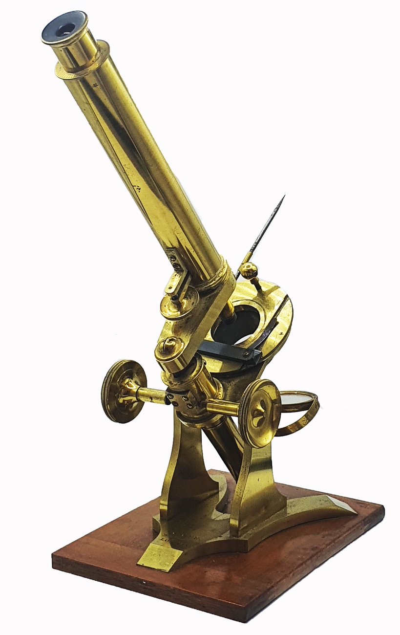 A gold microscope on a wooden standDescription automatically generated